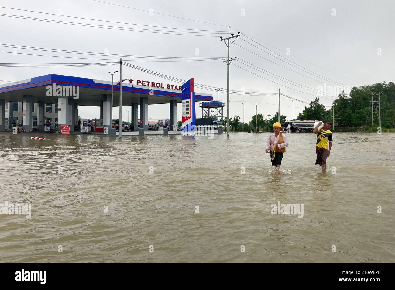 Local residents wade through a flooded road in Bago, about 80 ...