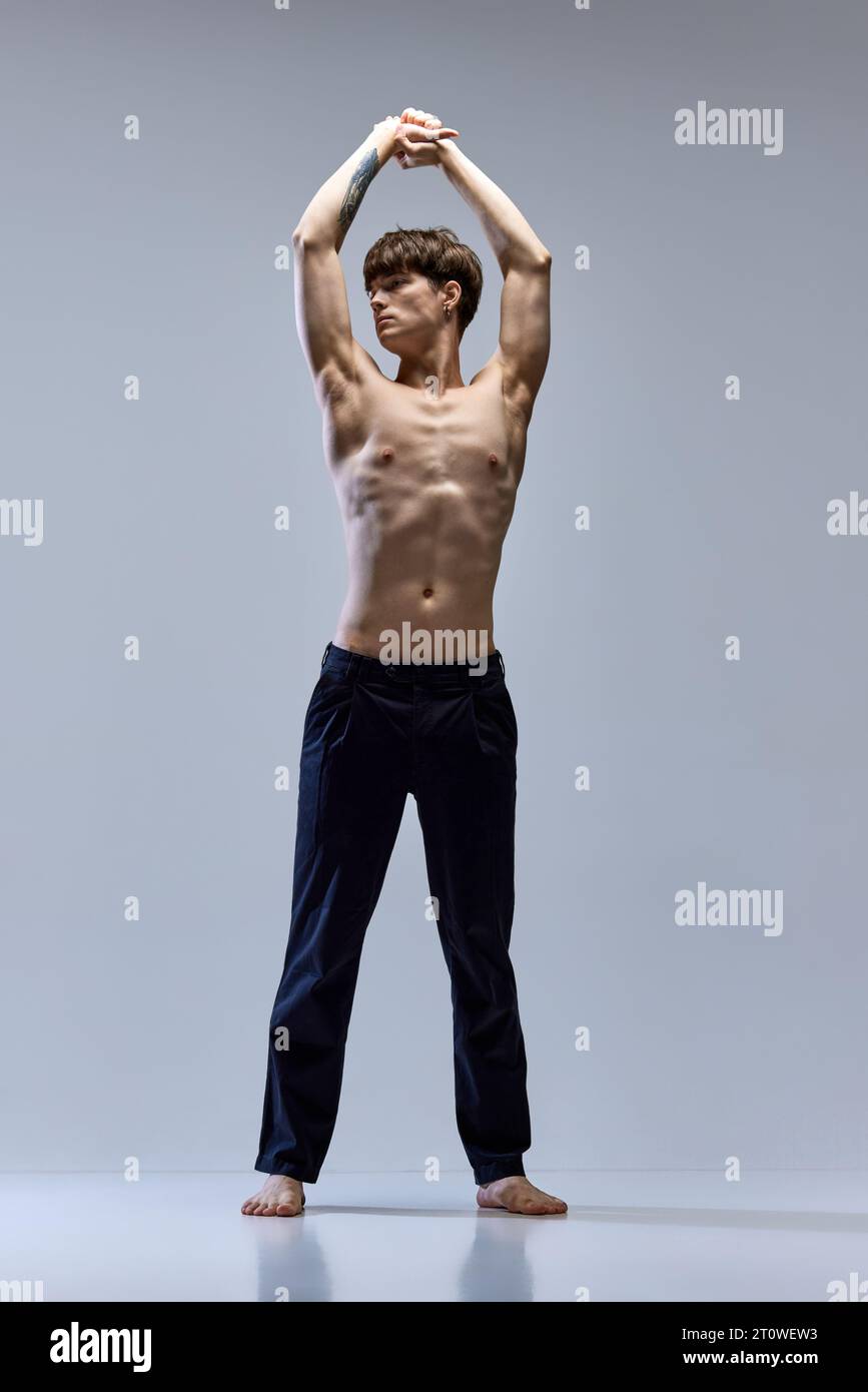 Portrait of young man posing looking away raising up in trousers ...