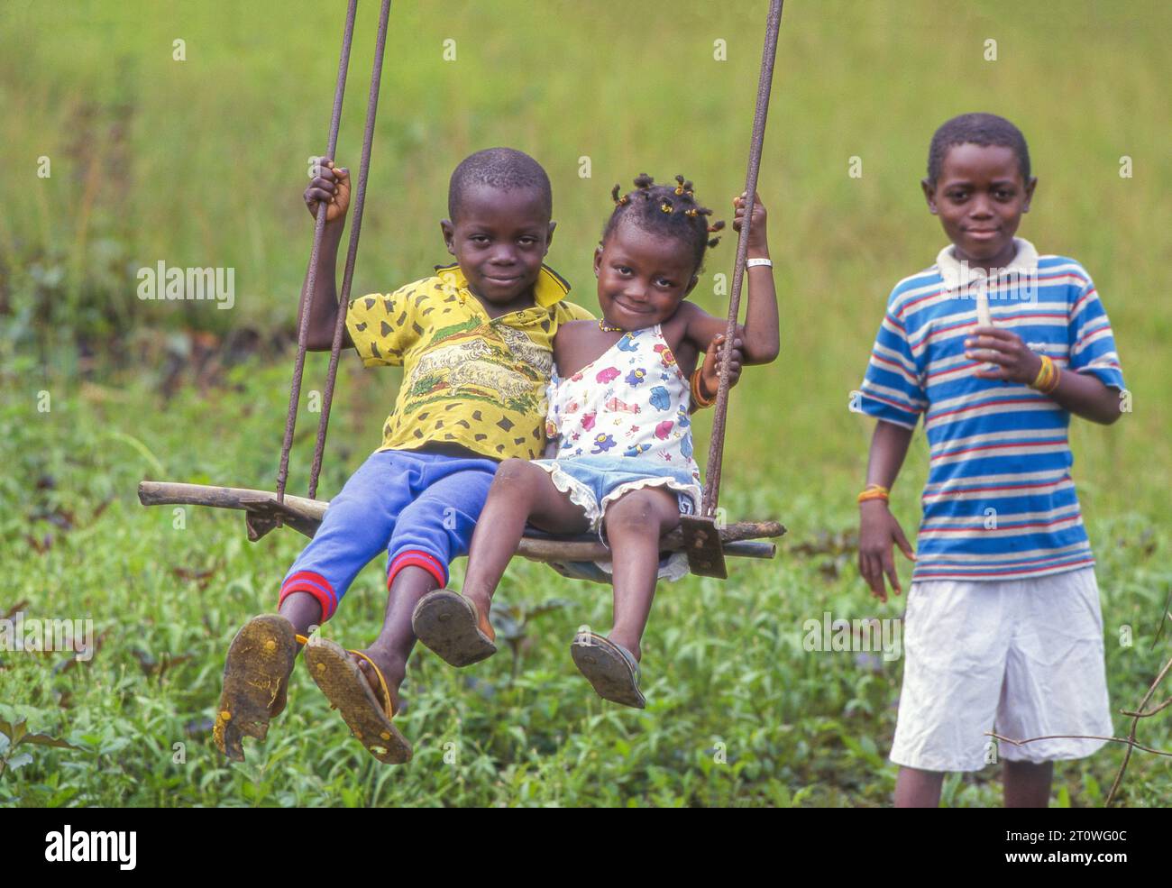 Liberia, boy pushes children on a swing in Harbel village Stock Photo ...