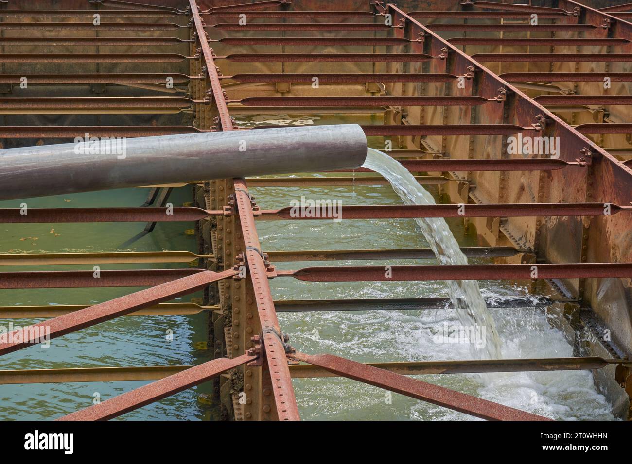 water pouring from pipe to large scale metal tanks for water supply ...
