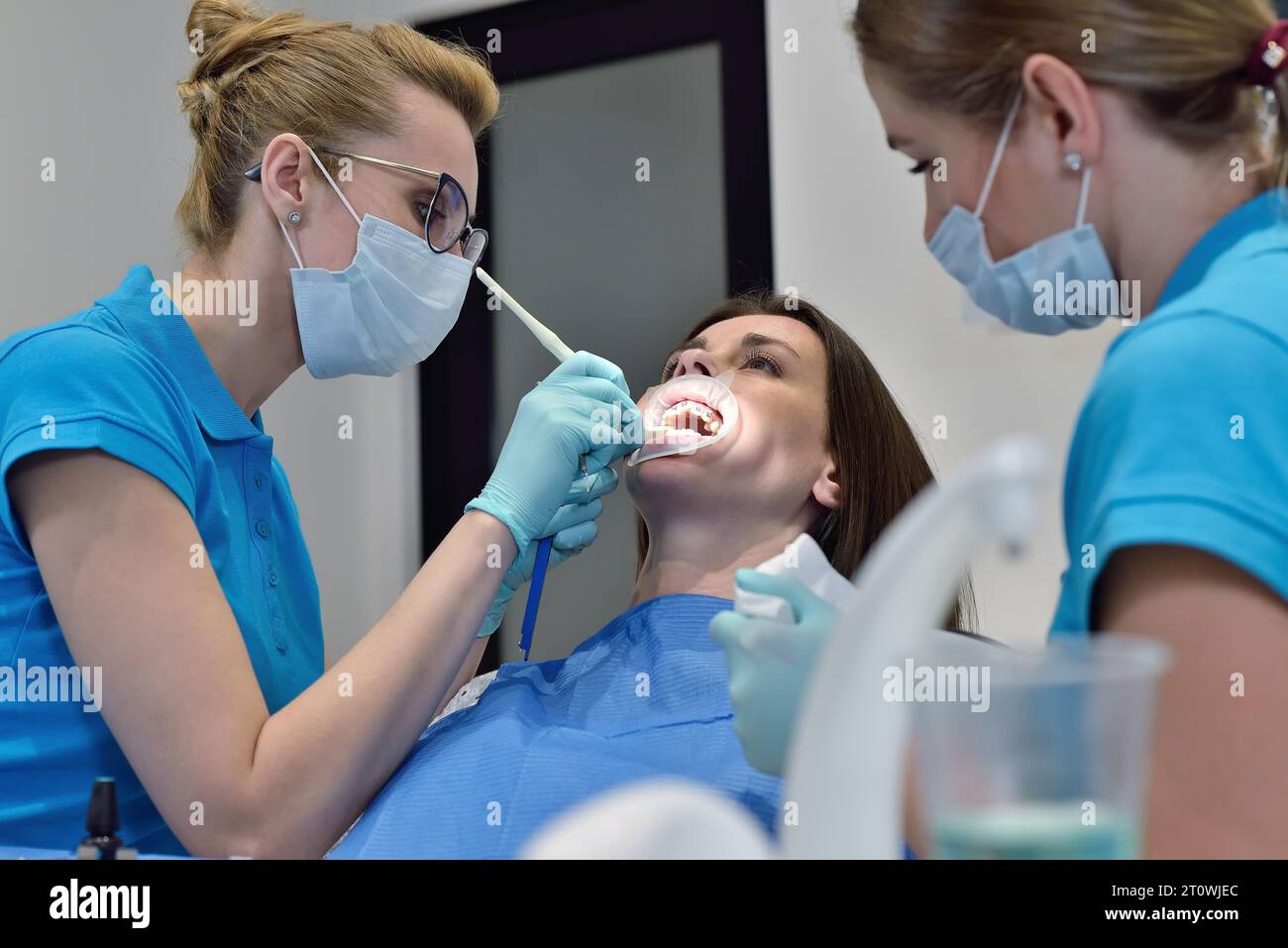 Woman Dentist And Assistant Examine Patient With Braces In Dental ...