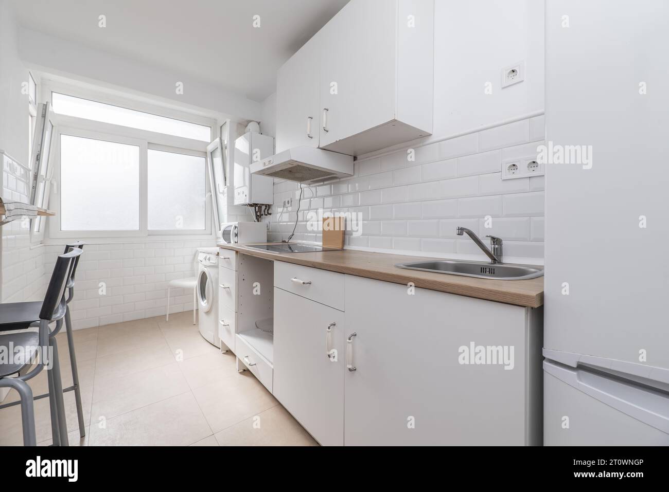 Furnished kitchen on one of the walls with white furniture, integrated ...