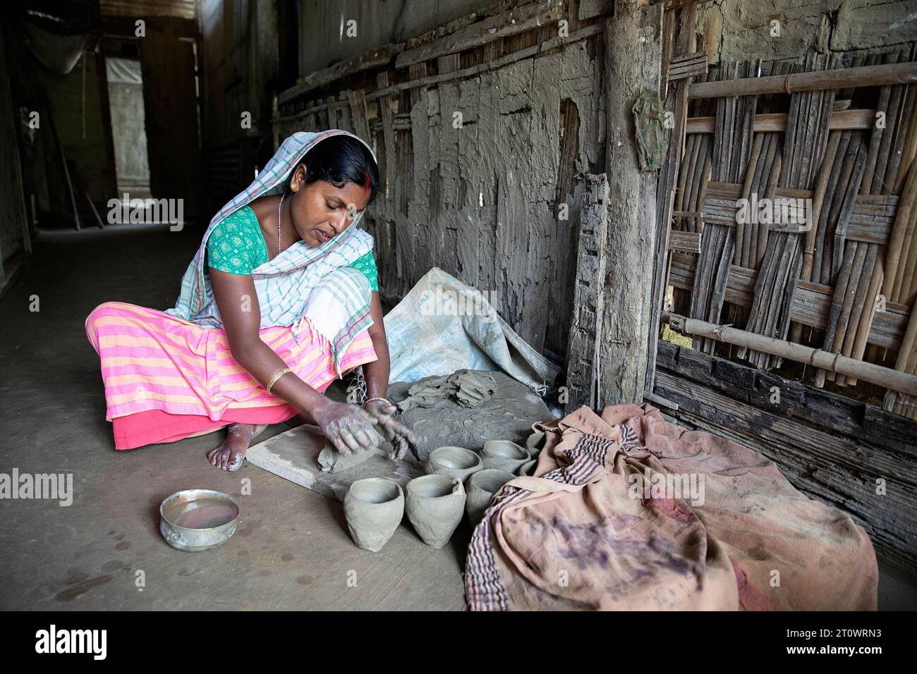 Indian woman making pottery on the floor in typical house, Majuli ...
