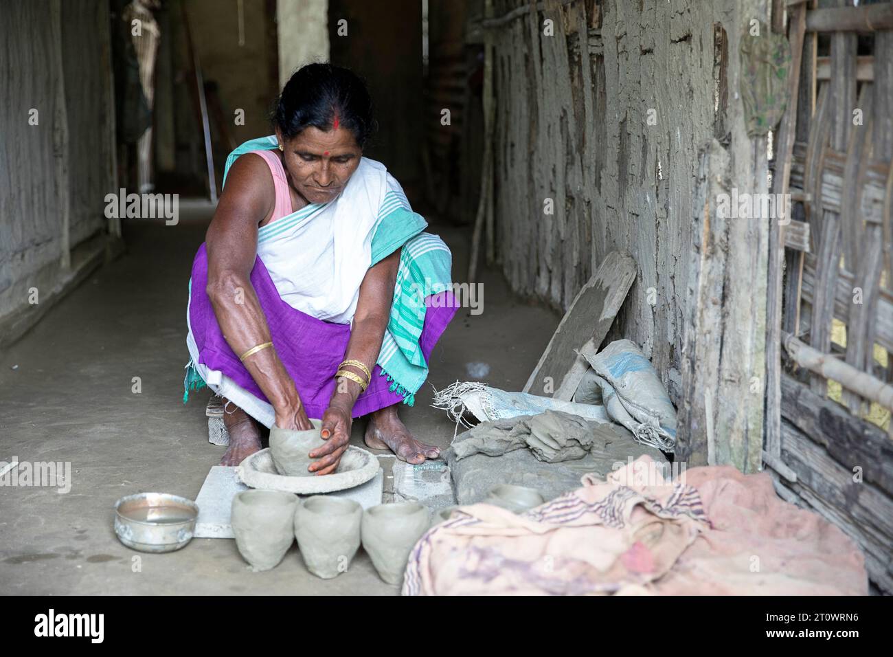 Indian woman making pottery on the floor in typical house, Majuli ...