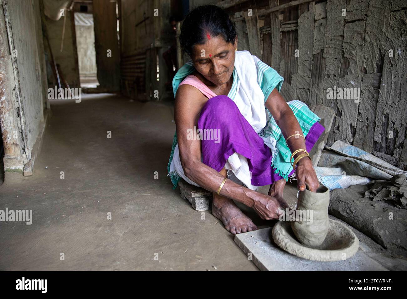 Woman in traditional indian clothes making pottery in his wooden house ...