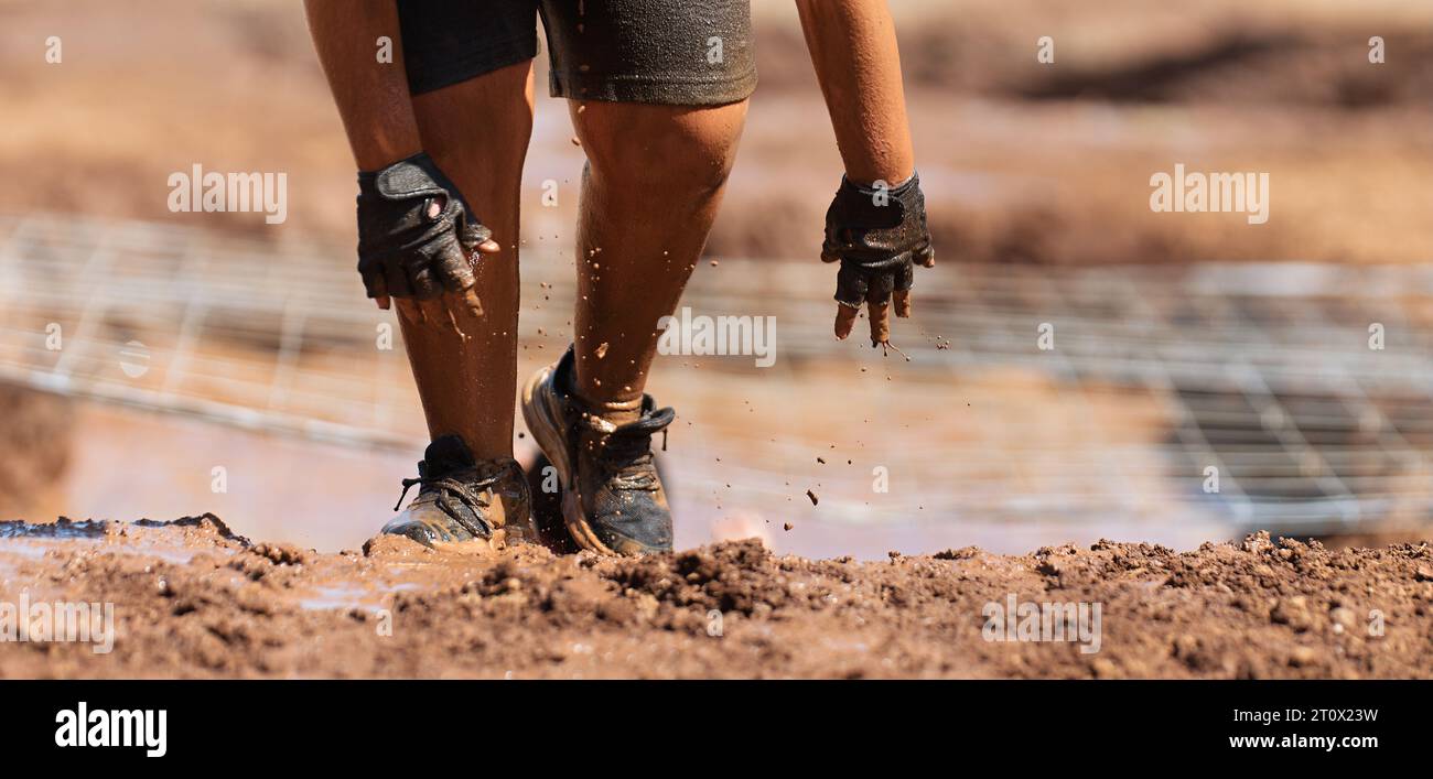 Mud race runners. Crawling, passing under a net obstacle during extreme ...
