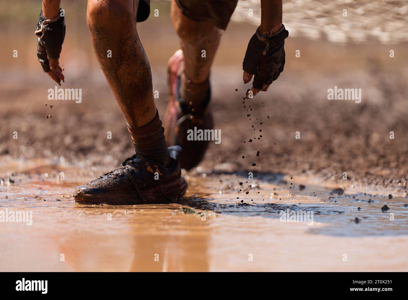 Mud race runners. Crawling, passing under a net obstacle during extreme ...
