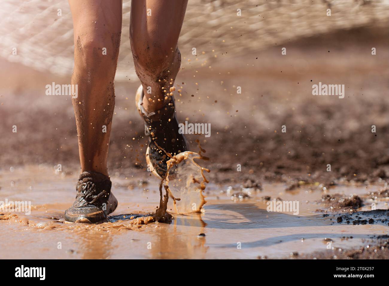 Mud race runners. Crawling, passing under a net obstacle during extreme ...