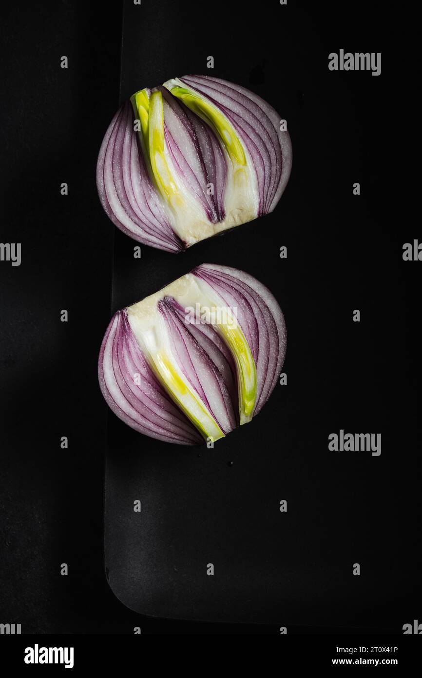 Red onion cut in half on a black background Stock Photo - Alamy