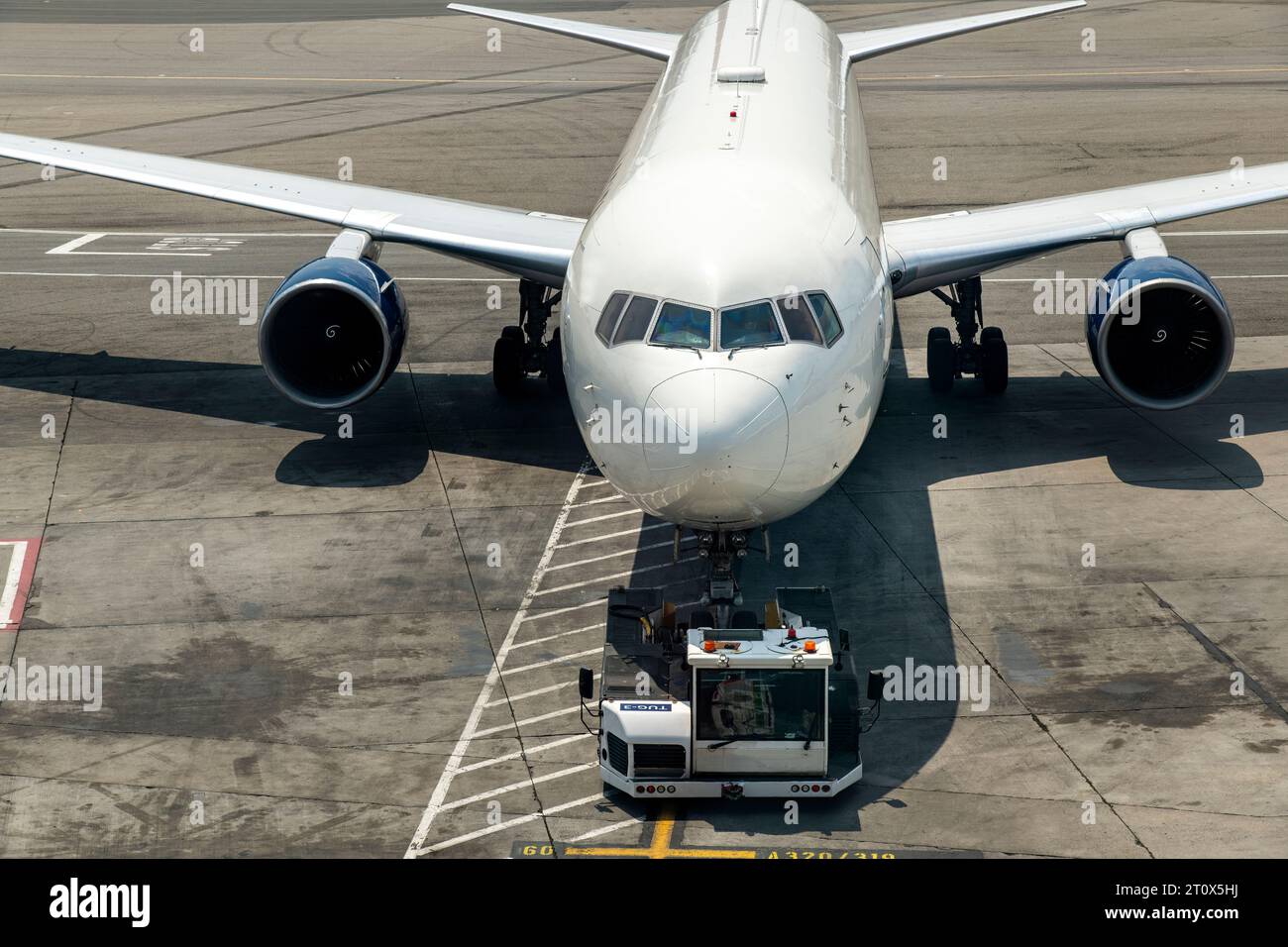 High angle view of aircraft being towed to jet bridge on yellow airport ...