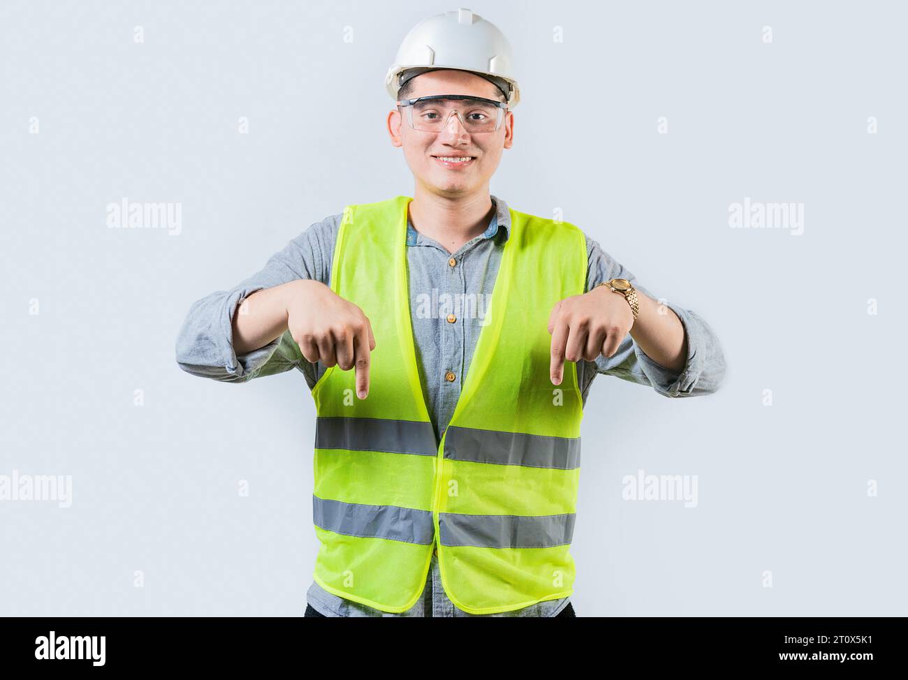 Smiling engineer pointing advertising down isolated. Smiling friendly ...
