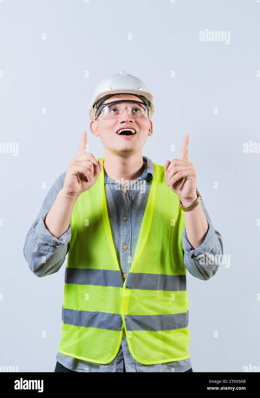 Surprised young architect pointing up. Amazed engineer pointing at an ...