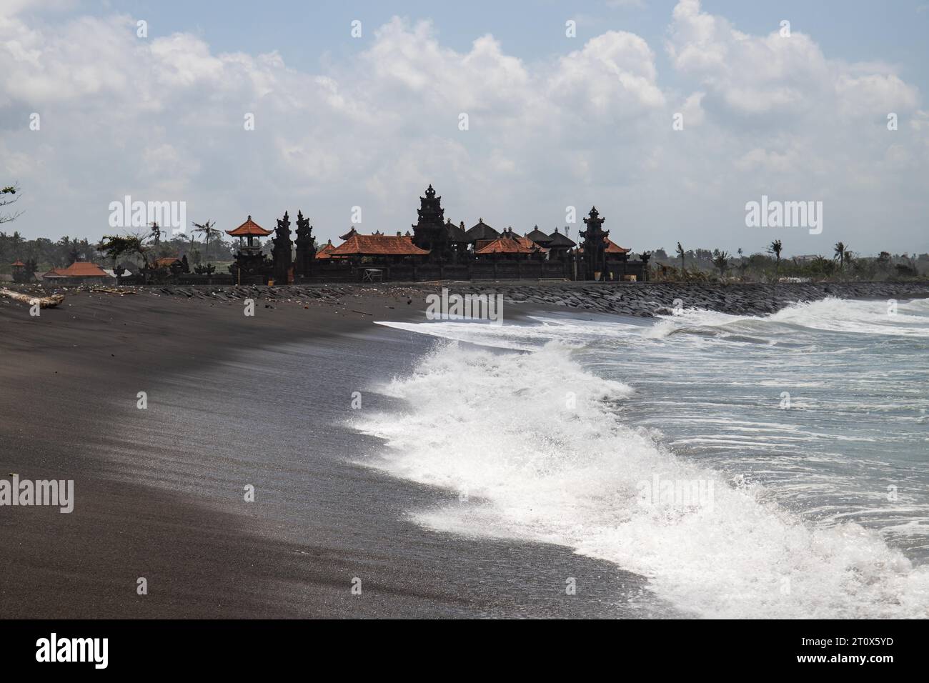 Hindu temple on a black sand beach directly by the sea. Evening ...