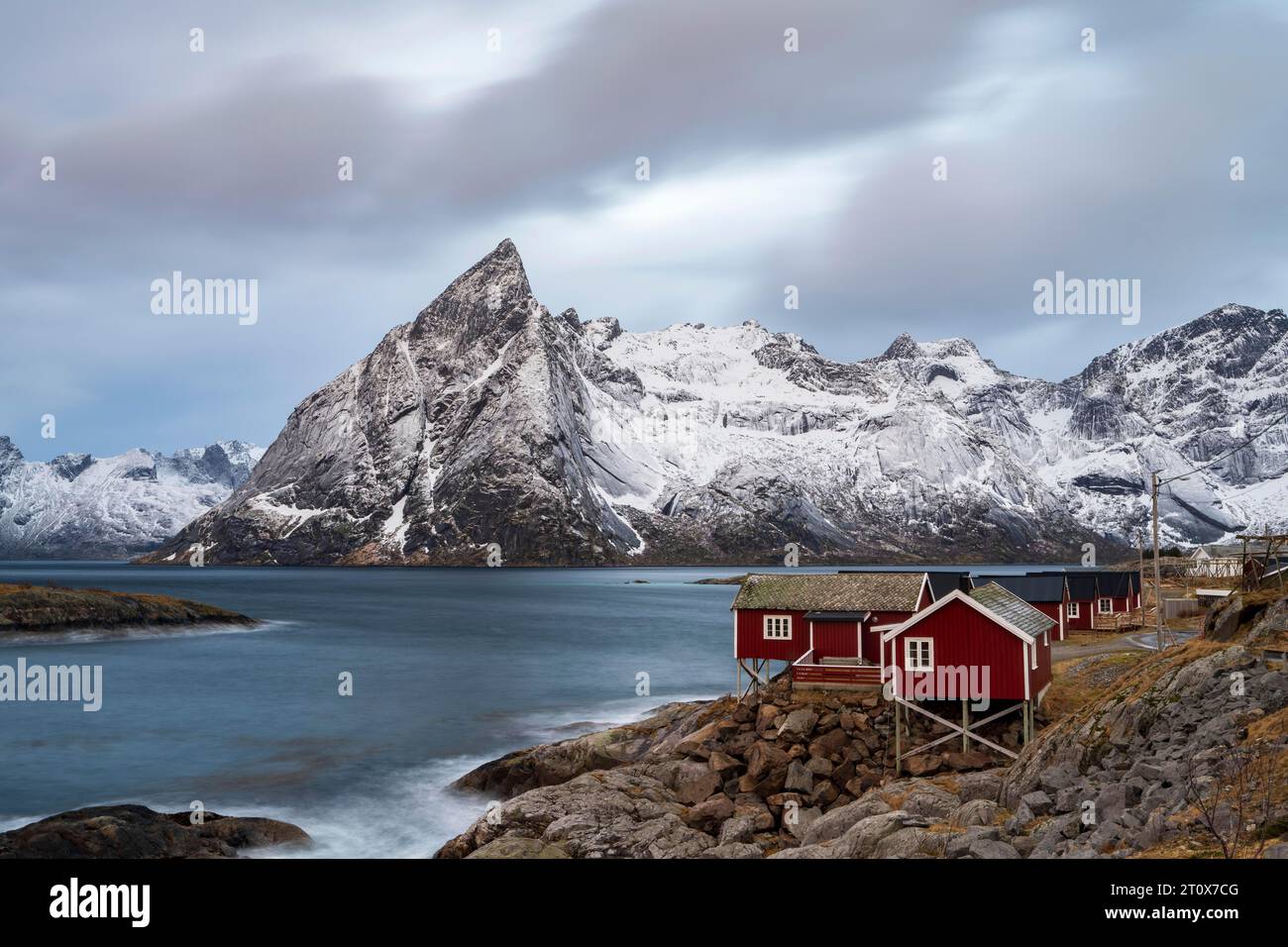 Rorbuer cabins of Hamnoy by the fjord, snowy mountains in the back ...