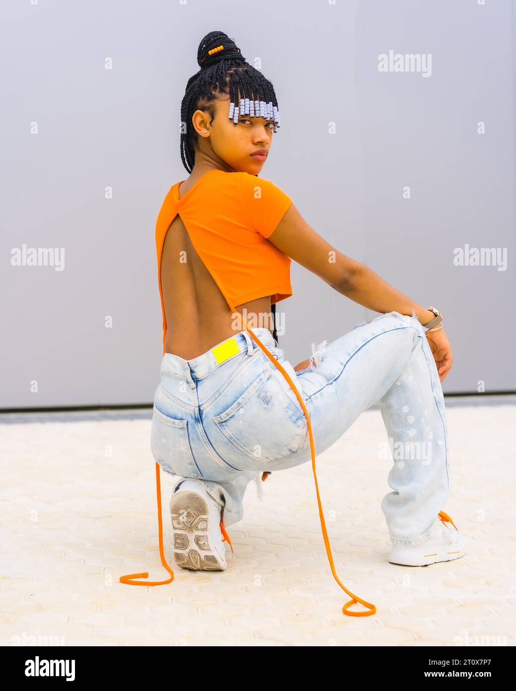 A young trap dancer with braids. Black ethnic girl with orange t-shirt ...