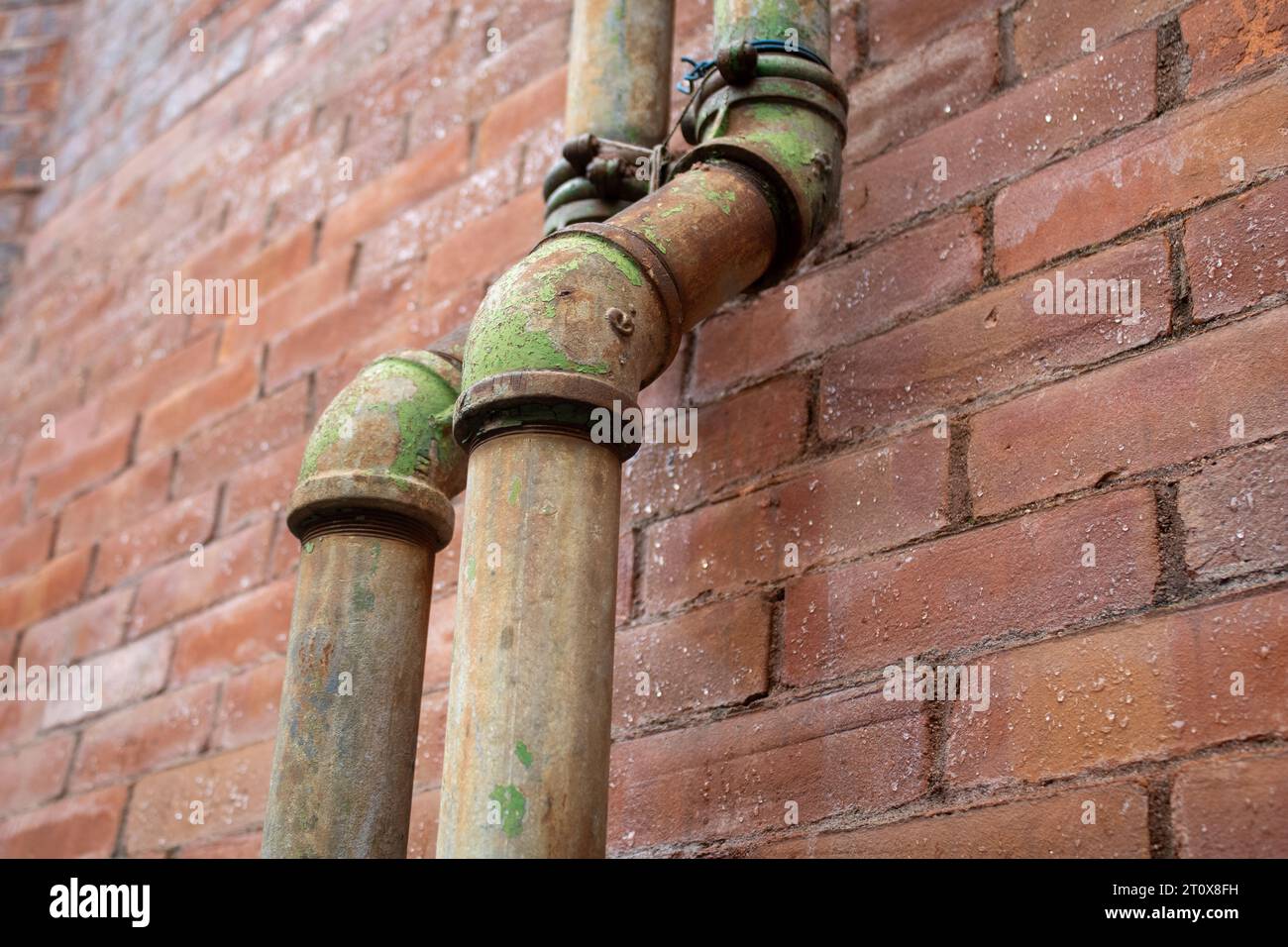 A closeup of a metallic pipe against brick buildings Stock Photo - Alamy