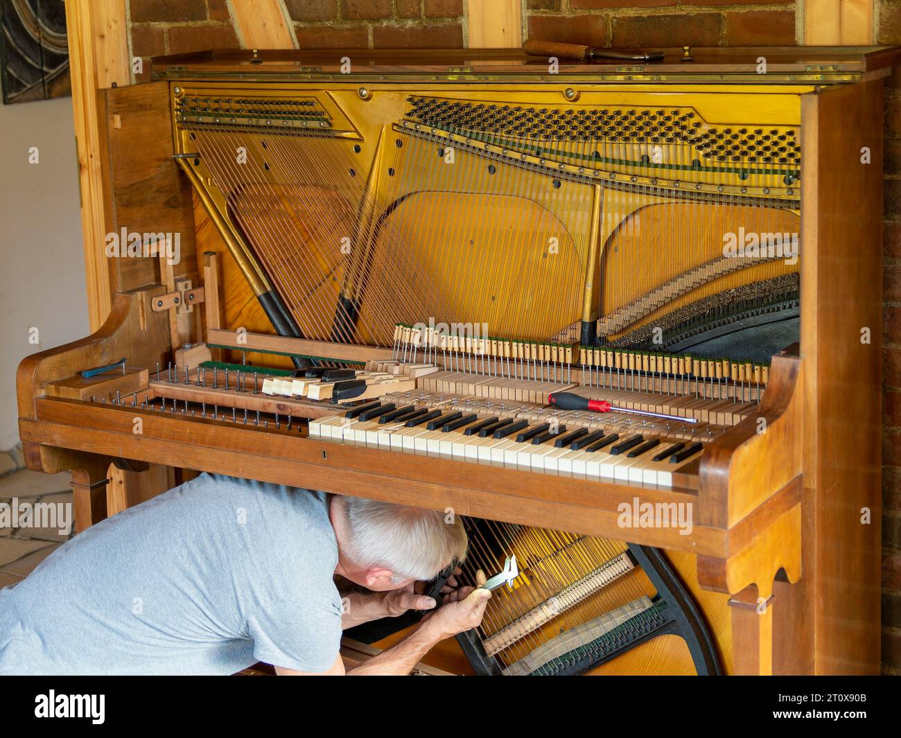 Piano maker repairing piano, piano tuner working on open old piano ...