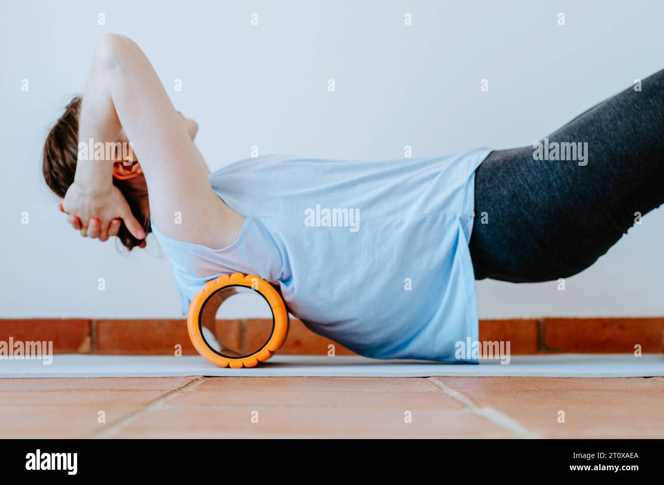 Woman rolling back on a foam massage roller to release tension in back ...