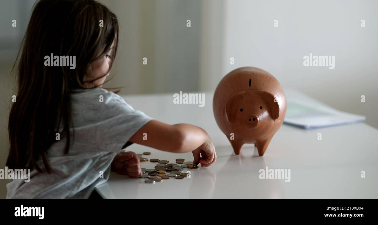 Child adding coins inside piggy bank Stock Photo - Alamy