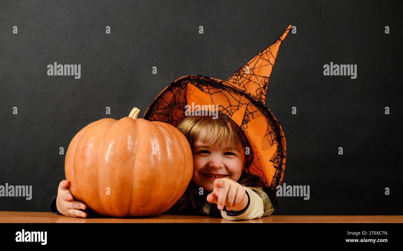 Happy child in Halloween costume with magic pumpkin. Kids trick or ...