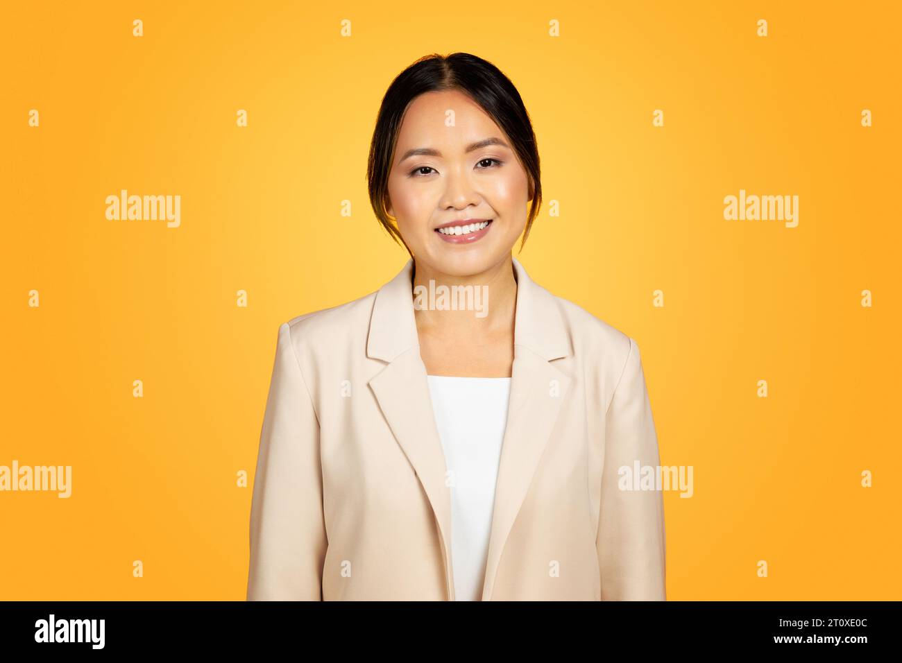 Joyful Asian millennial woman smiling warmly, posed against a bright ...