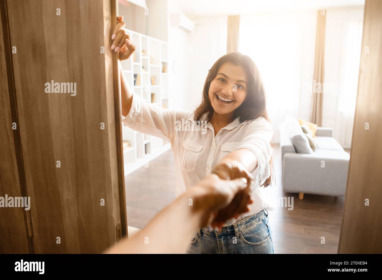 Indian woman by open door, warmly shaking hands with guest Stock Photo ...