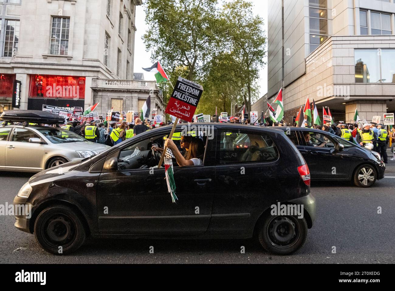 London, UK. 9 October 2023. Palestine supporters drive by waving a sign ...