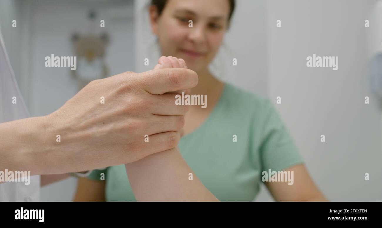 Close up of female doctor checking development of hip joints of baby ...