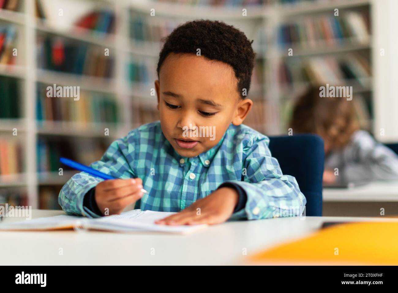 Focused schoolboy writing in copybook during lesson in classroom Stock ...