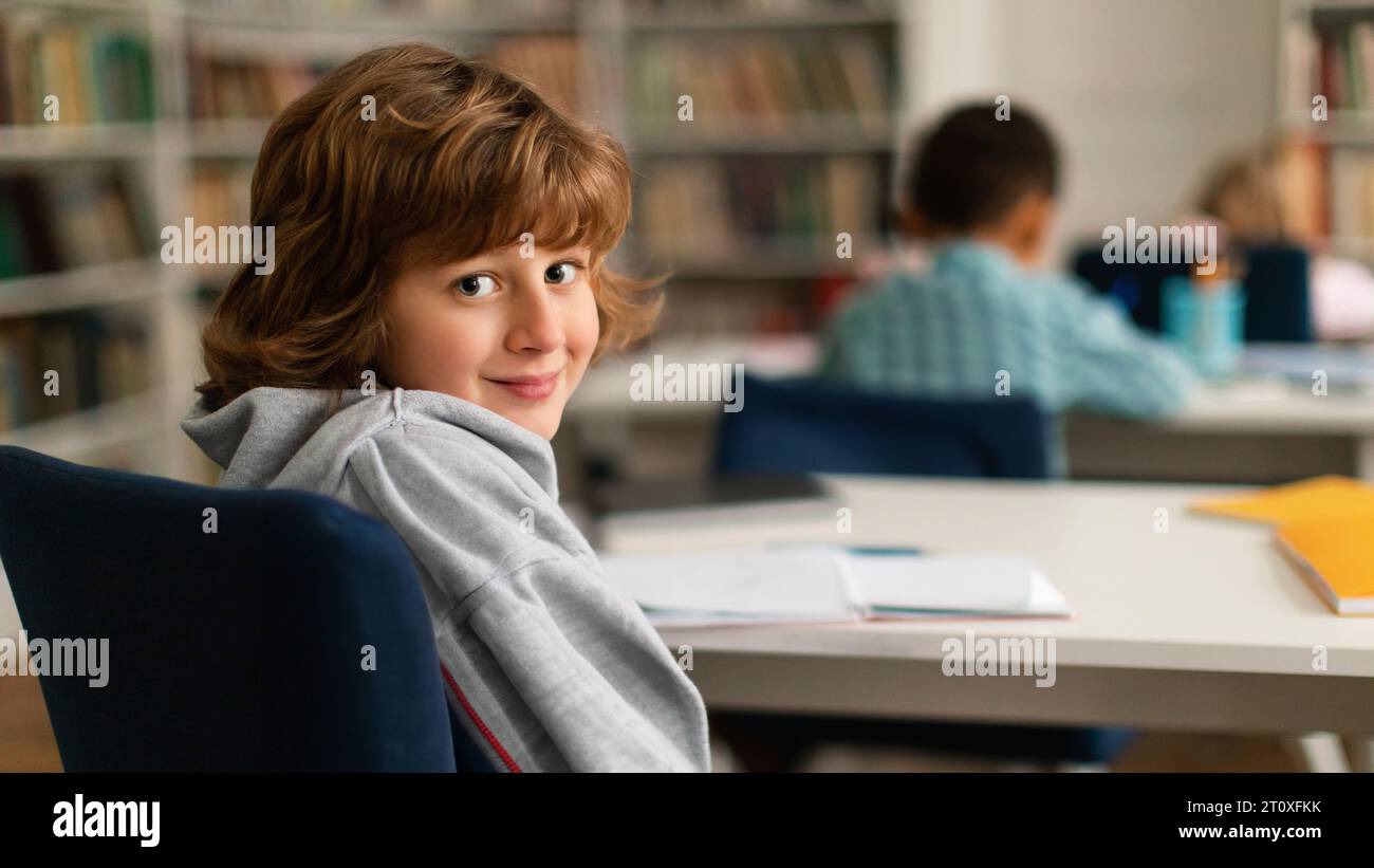 European schoolboy turning back, smiling at camera in class Stock Photo ...