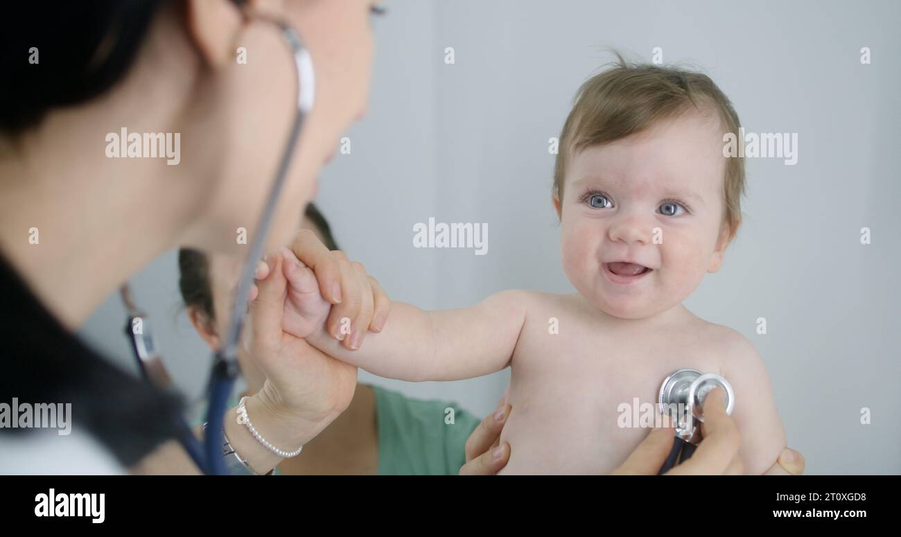 Pediatrician applies stethoscope to back of handsome little child to ...