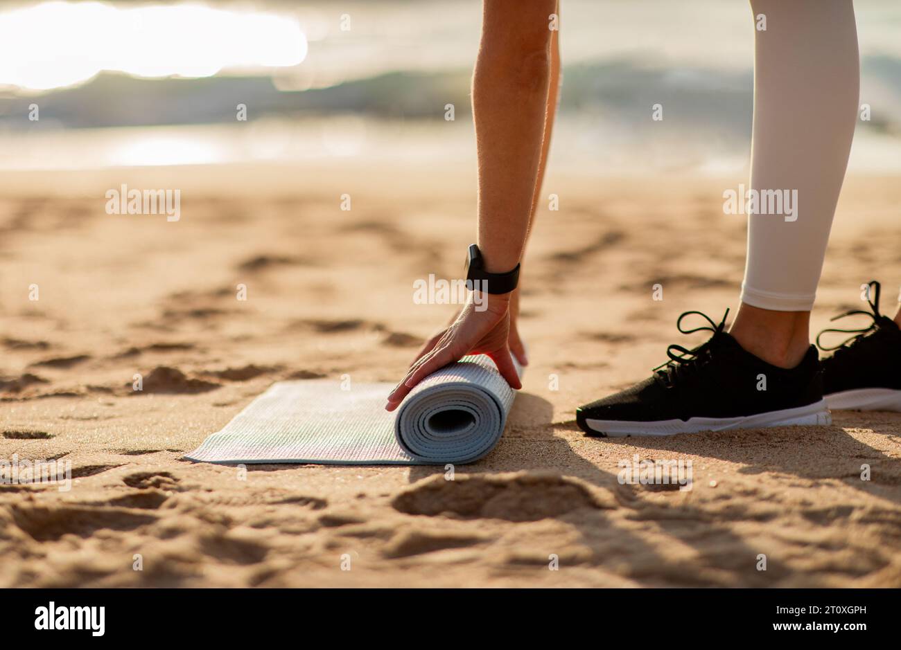 Fit lady putting mat on sand, preparing for training on ocean beach at ...