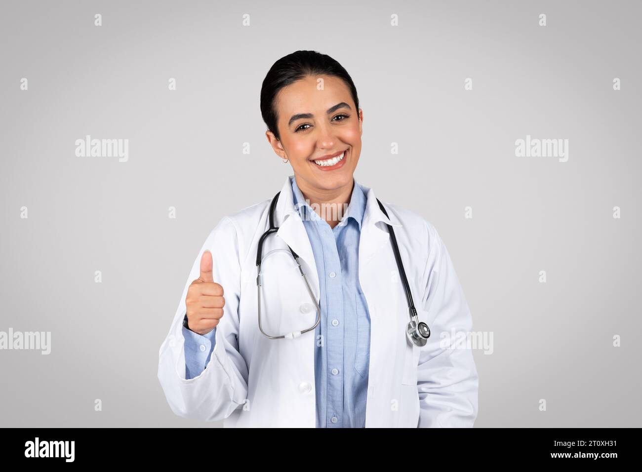 Smiling woman doctor giving thumb up in studio, approving medical offer ...