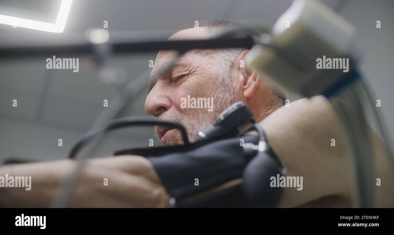 Elderly man with tonometer and holter sensors pedals orbitrek in ... Elderly man with tonometer and holter sensors pedals orbitrek in ...