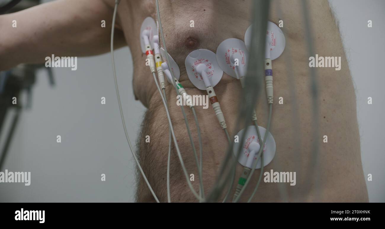 Elderly man with holter sensors pedals orbitrek in cardiology room ... Elderly man with holter sensors pedals orbitrek in cardiology room ...