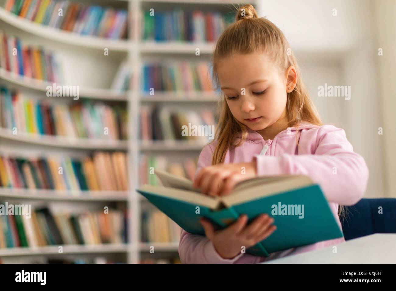 Schoolgirl attentively leafing through a book Stock Photo - Alamy