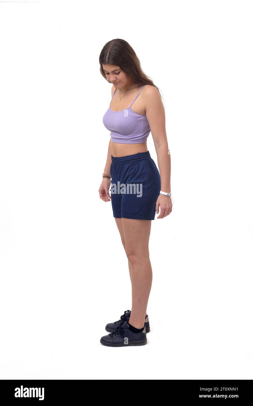 side view of a young girl standing looking down on white background ...