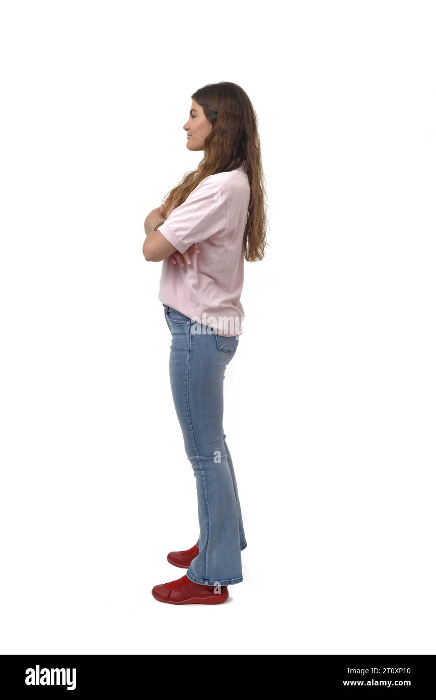 side view of a young girl standing and arms crossed on white background ...