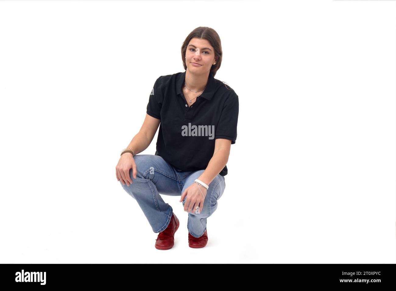 front view of a young girl squatting and looking at camera on white ...