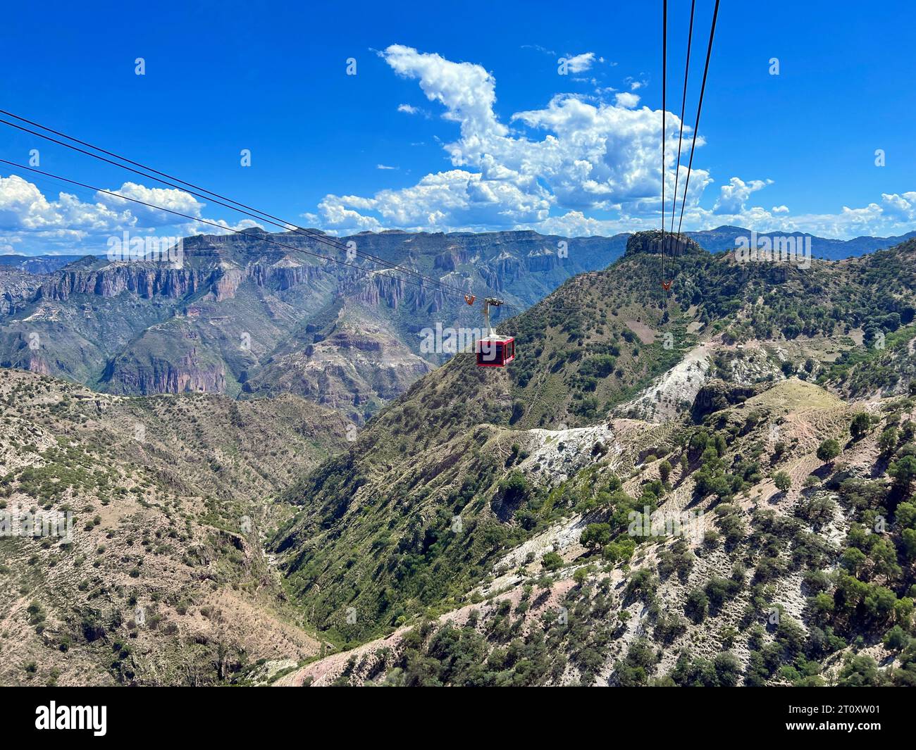 A sunlit panoramic view of Copper Canyon, with a cable car full of ...