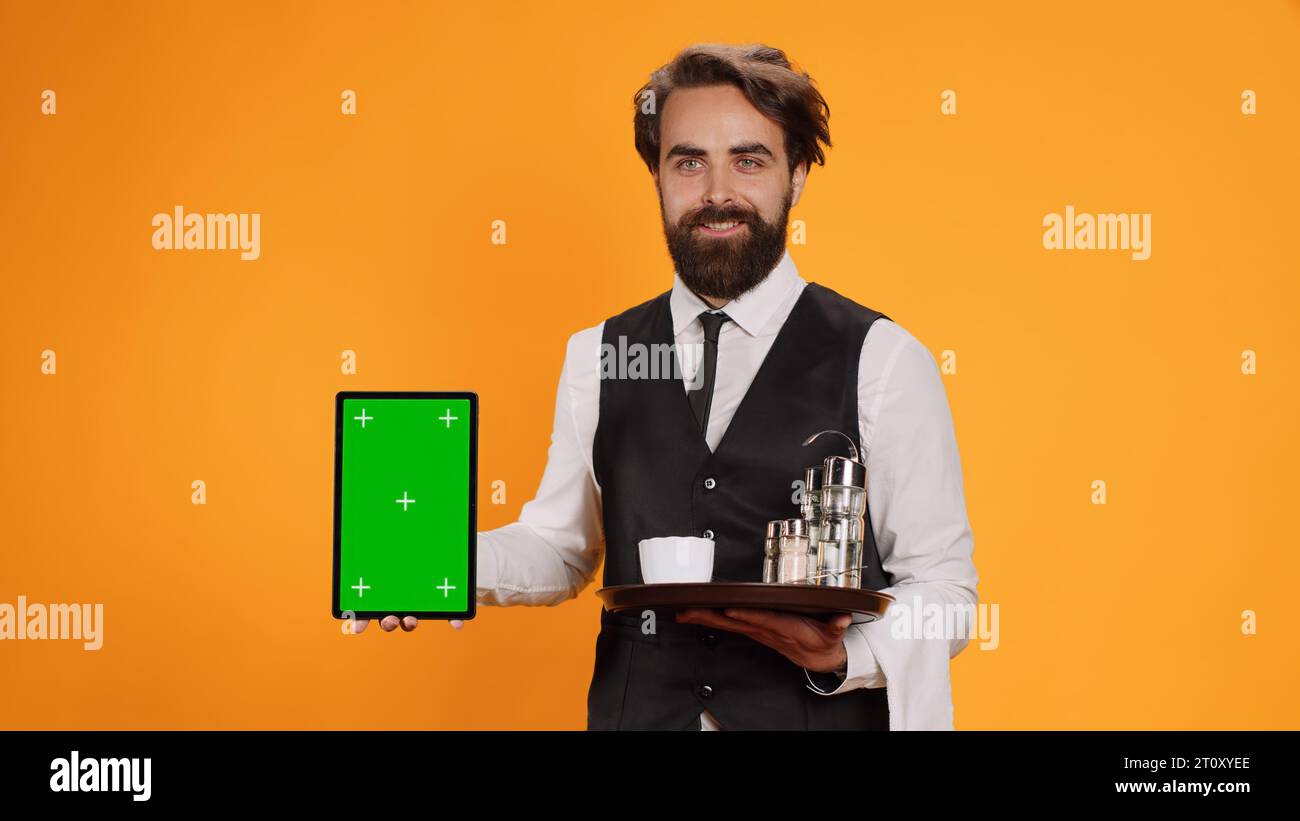 Friendly waiter shows tablet with greenscreen on camera, presenting ...