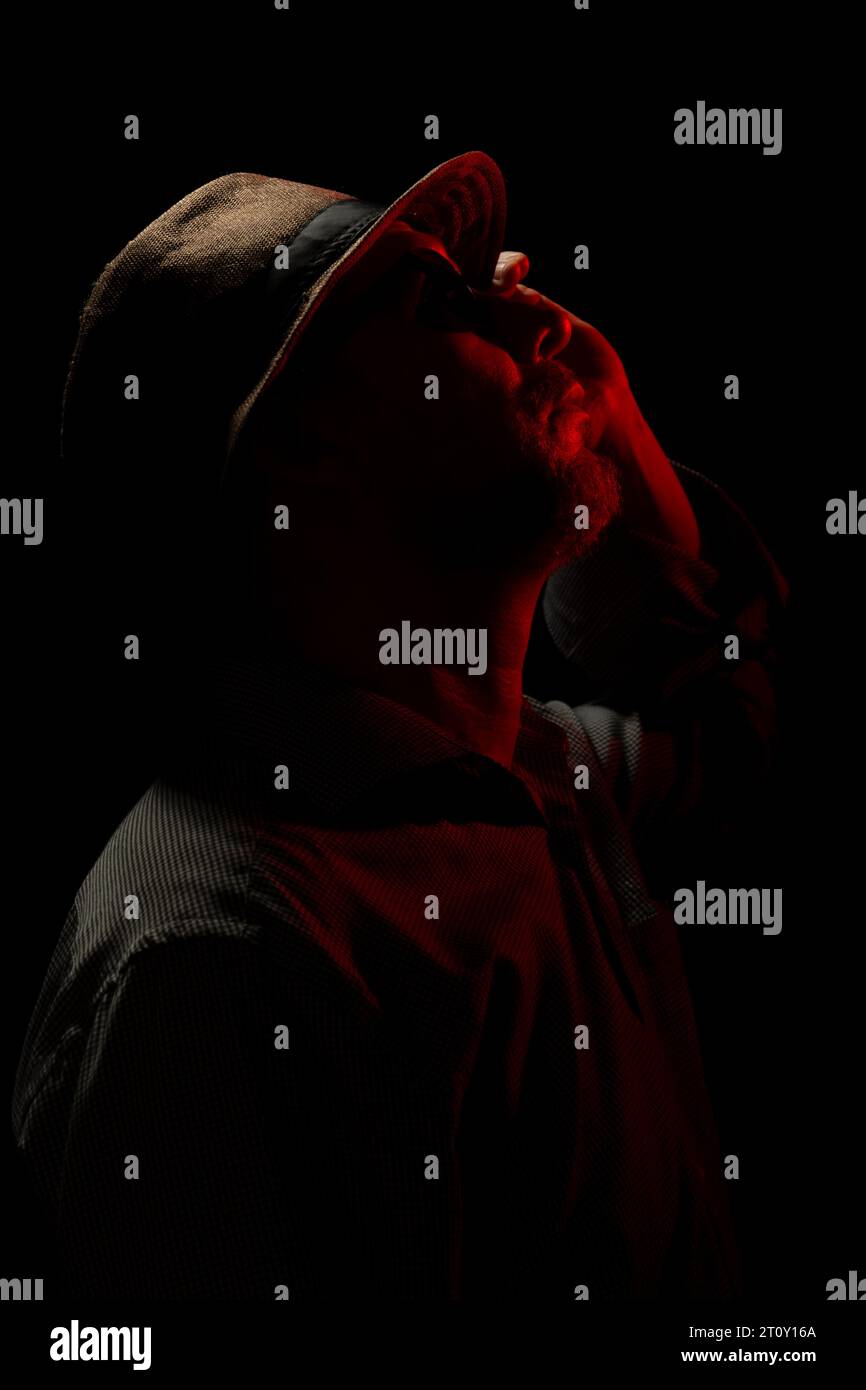 Discreet portrait of man wearing hat and sunglasses in darkness with ...