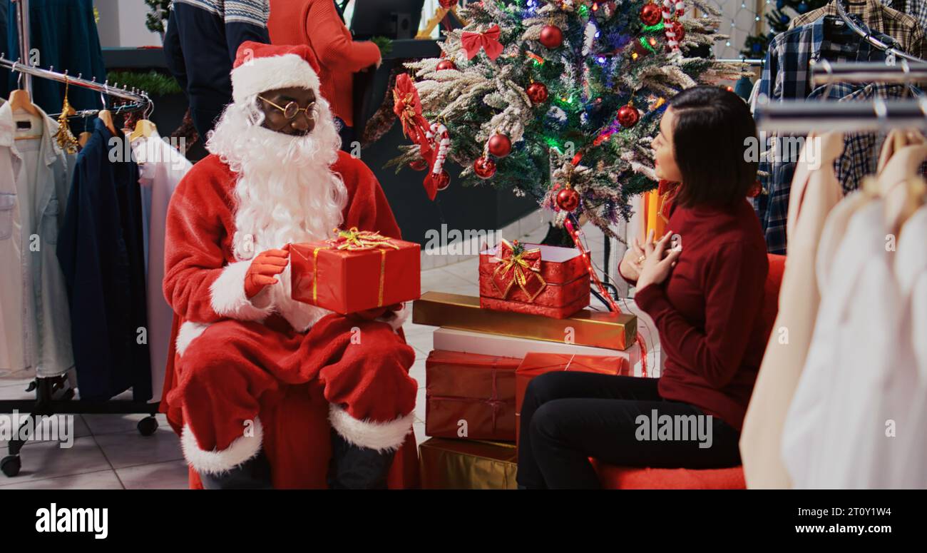 Retail assistant wearing Santa Claus costume around shopping mall ...