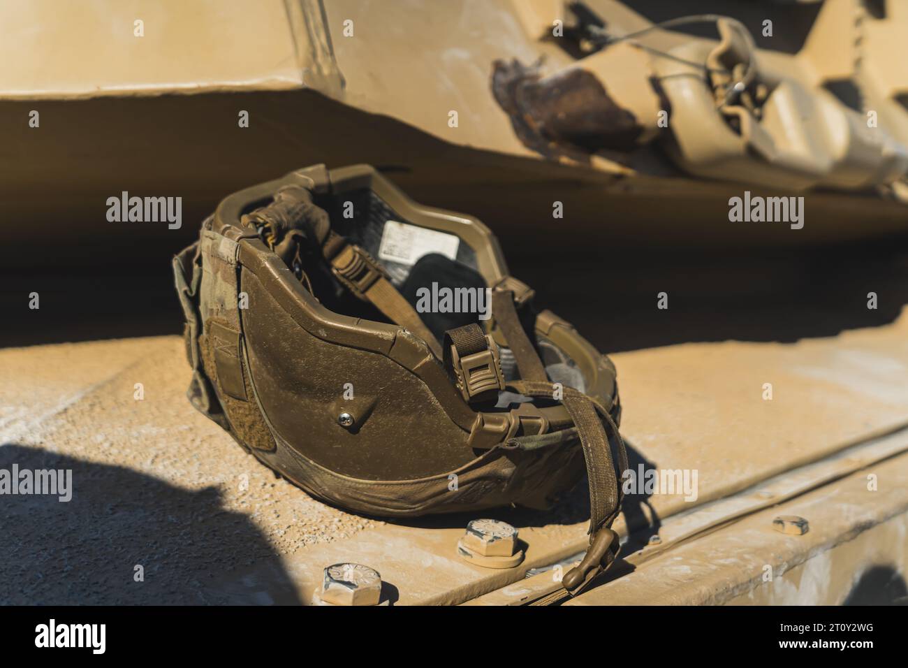 Dark-coloured military helmet lying upside down on a military US tank ...