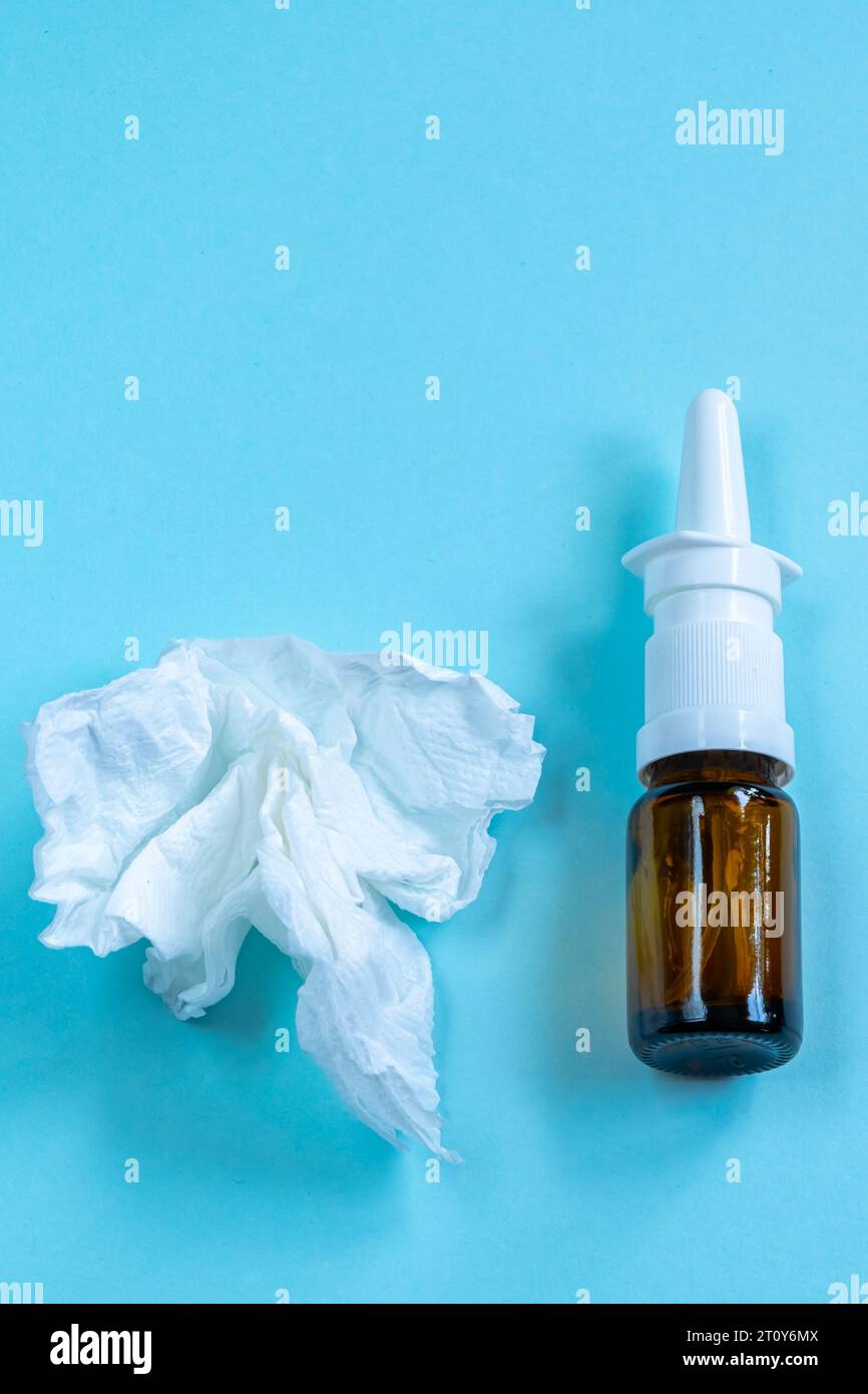 Nasal spray for runny nose and crumpled paper tissues on blue ...
