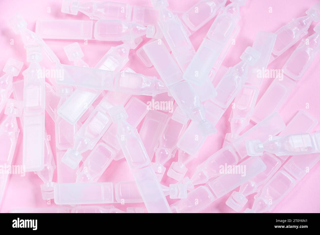 Medical eye drops in plastic pipettes on pink background. Pile of empty ...
