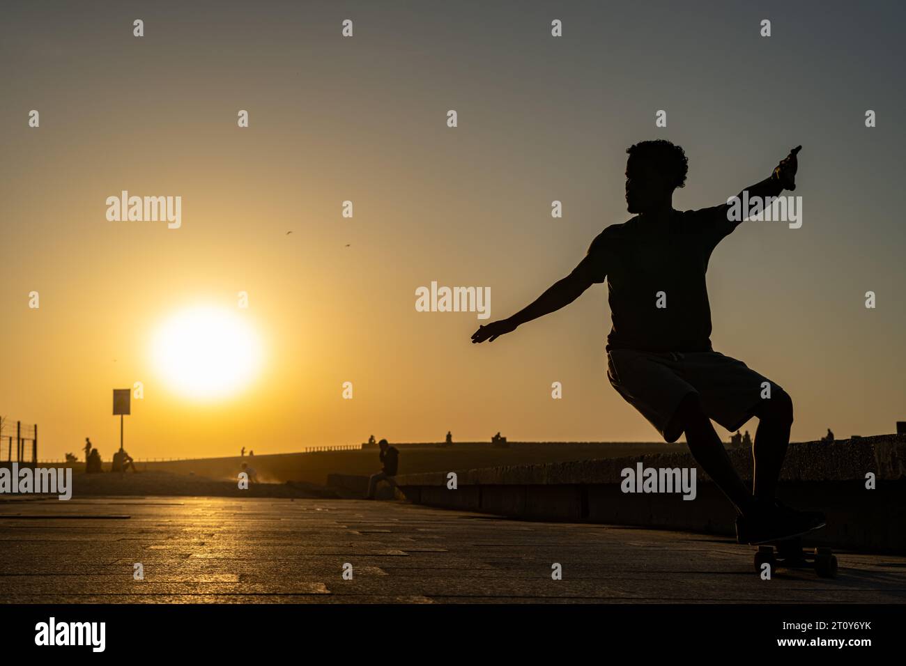 Surf skater training surfing moves near the beach at sunset Stock Photo ...