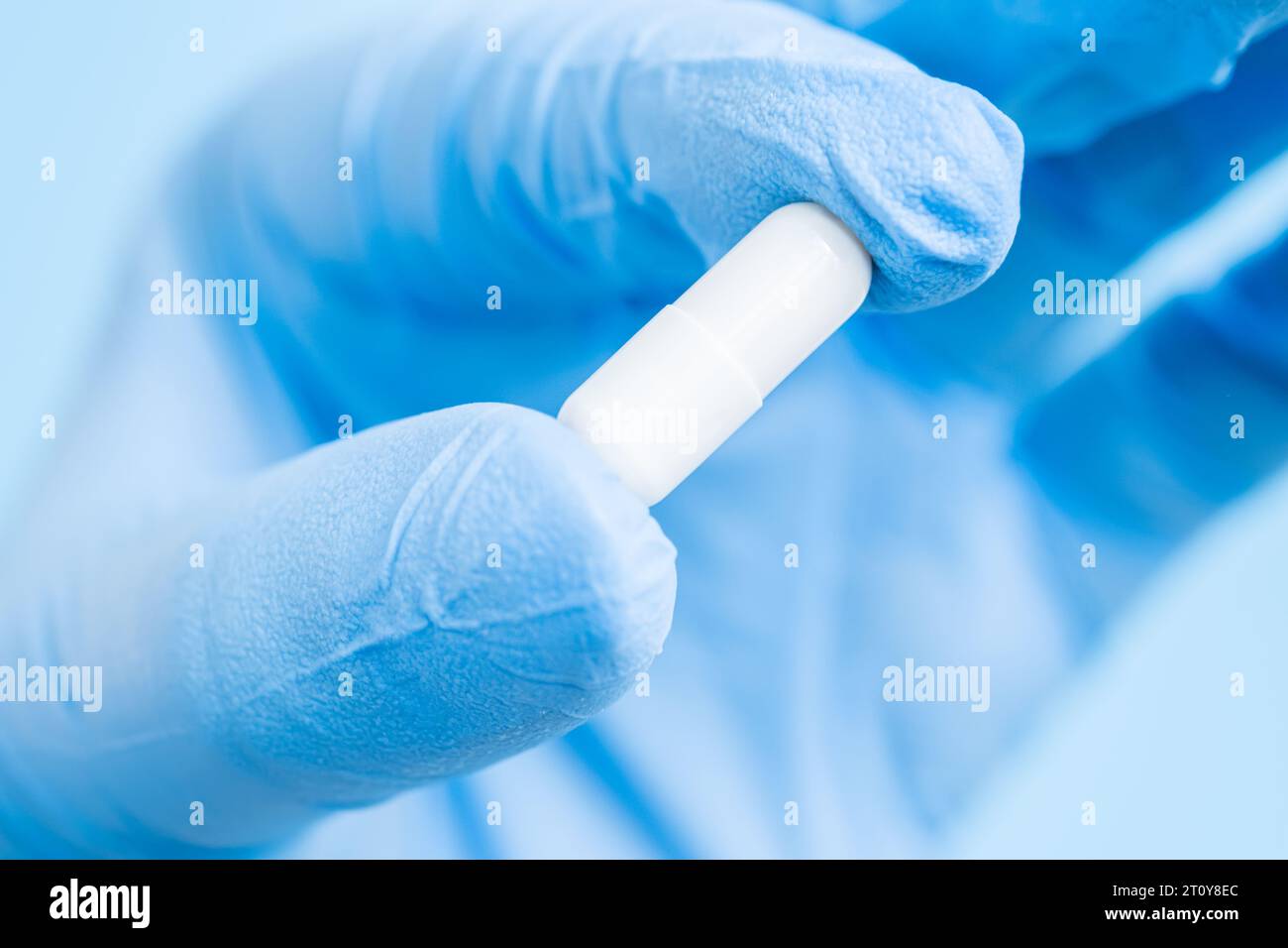 Doctor, pharmacist or scientist hand in glove holding white capsule of ...