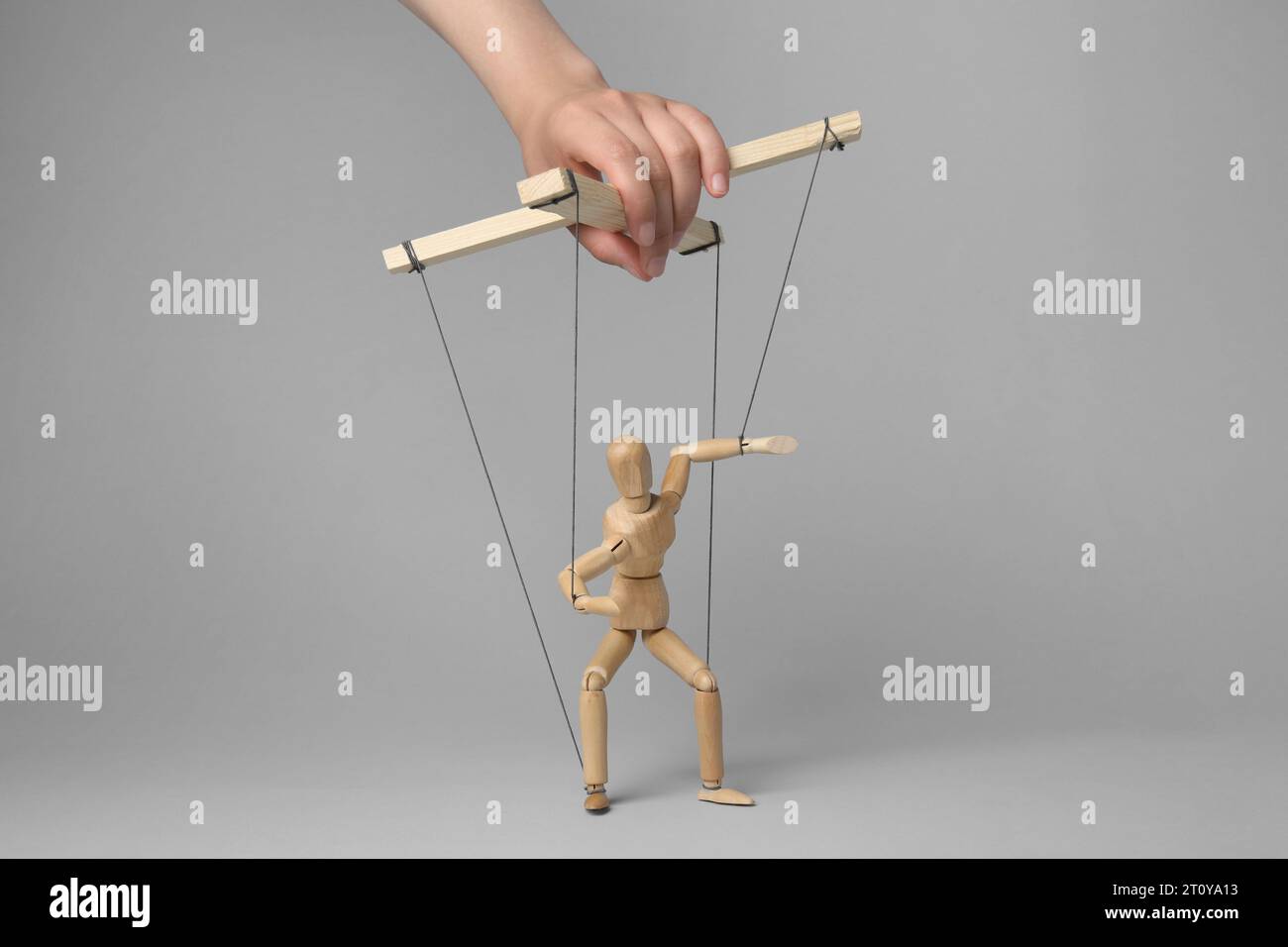 Woman pulling strings of puppet on light grey background, closeup Stock ...