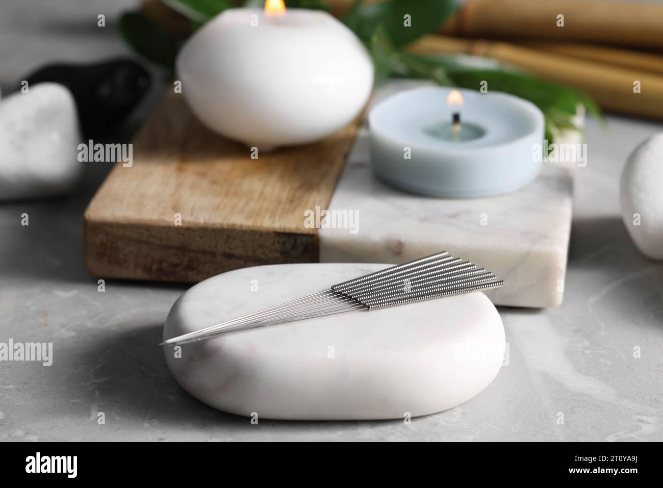 Stone with acupuncture needles on light grey marble table Stock Photo ...